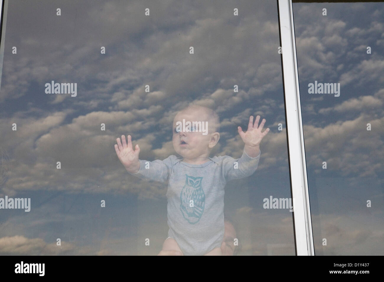 Baby in a window with reflections of clouds Stock Photo - Alamy