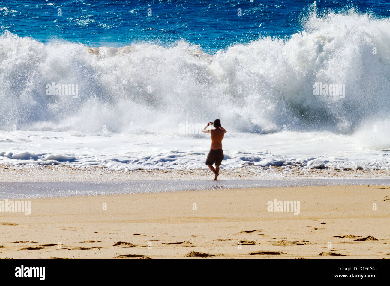 A young man takes a picture of crashing surf on a beach near Todos ...
