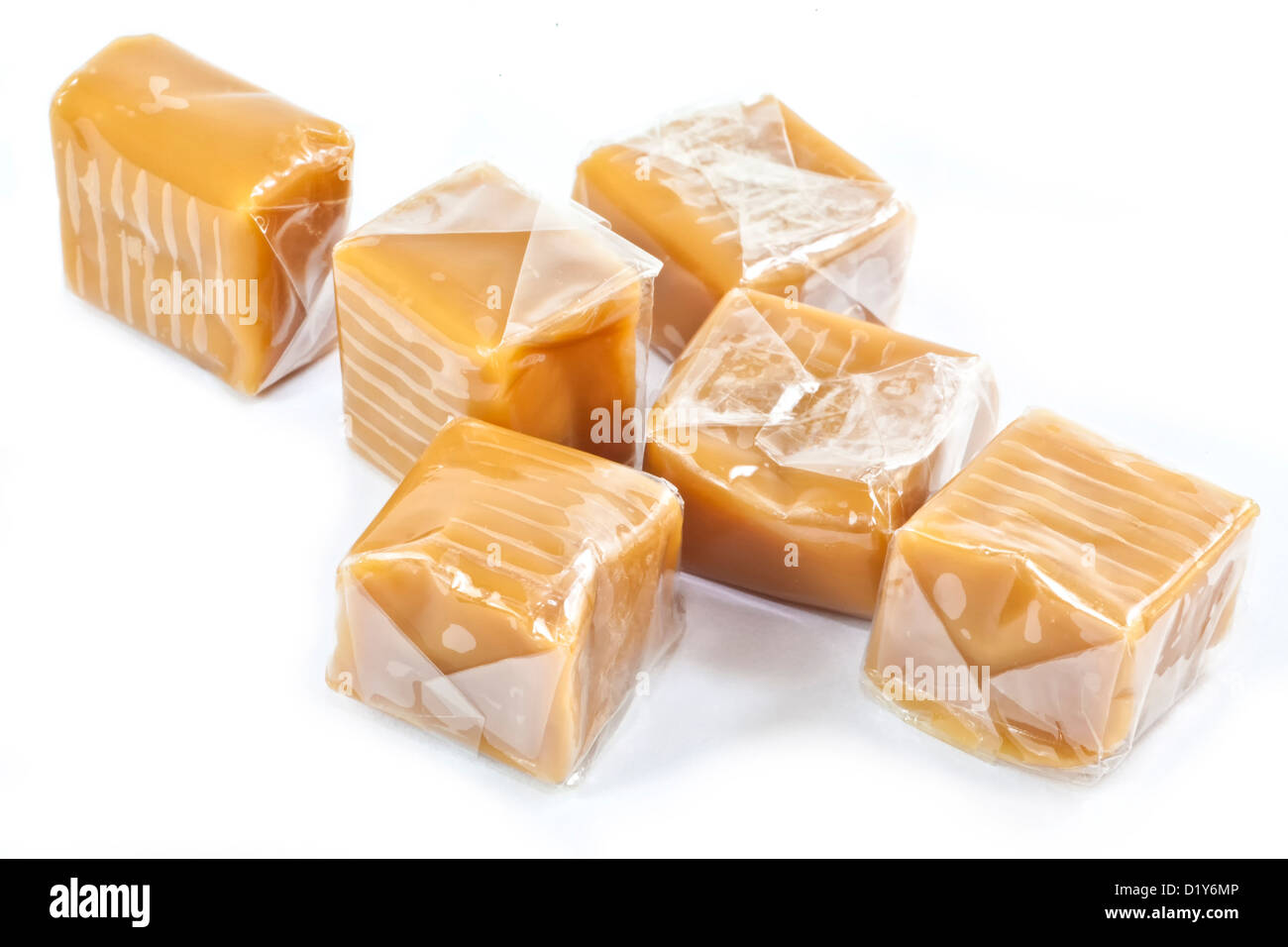 Caramel candies, each wrapped with a clear cellophane, on a white ...