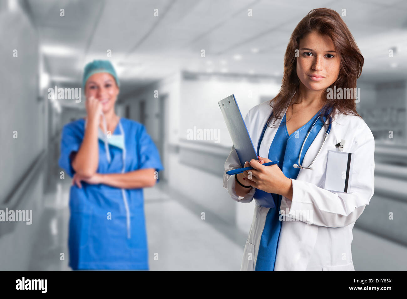 Female doctor writing in a notepad inside an hospital. Another female ...