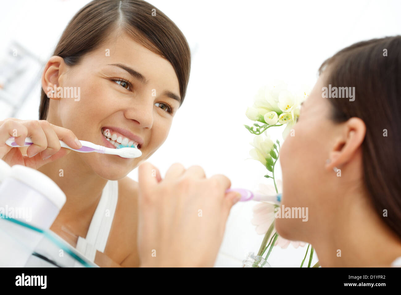 Image Of Pretty Female Brushing Her Teeth In Front Of Mirror In The