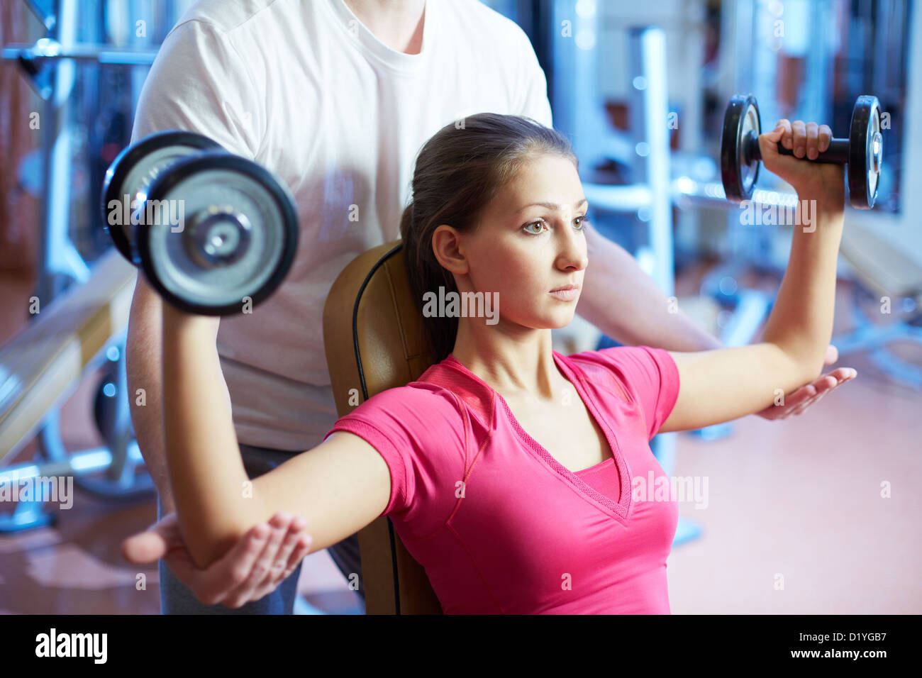 Portrait of pretty girl training in gym with her trainer helping her ...