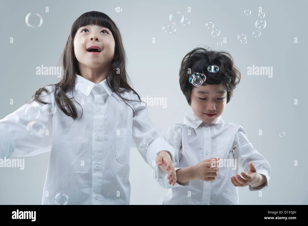 a female and a male kids trying to catch bubbles Stock Photo - Alamy
