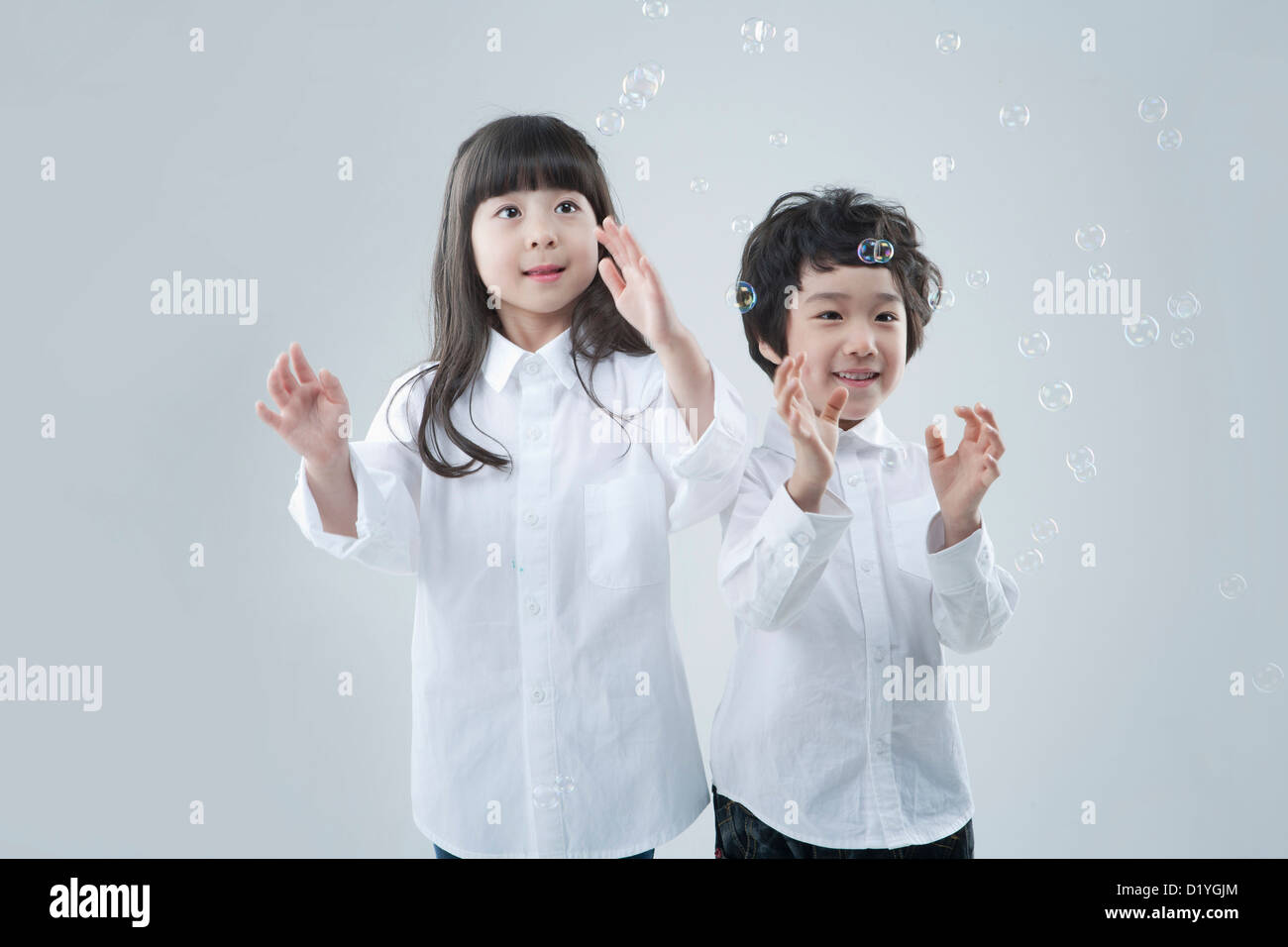 a female and a male kids trying to catch bubbles Stock Photo - Alamy