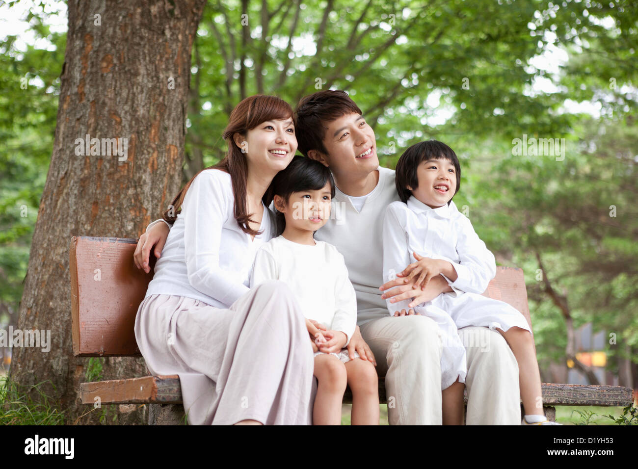 a family sitting on a bench smiling Stock Photo - Alamy