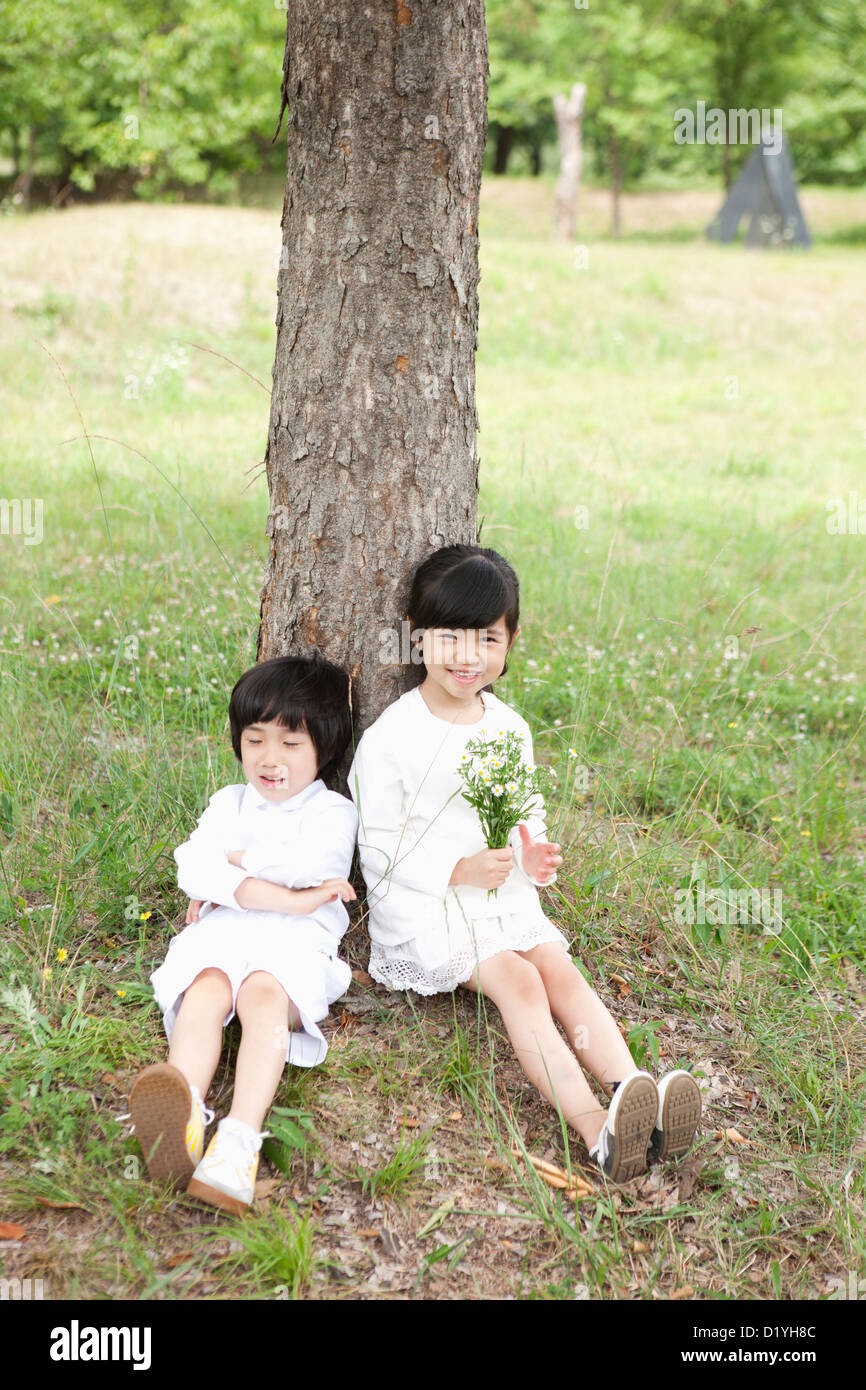 two kids sitting under a tree Stock Photo - Alamy