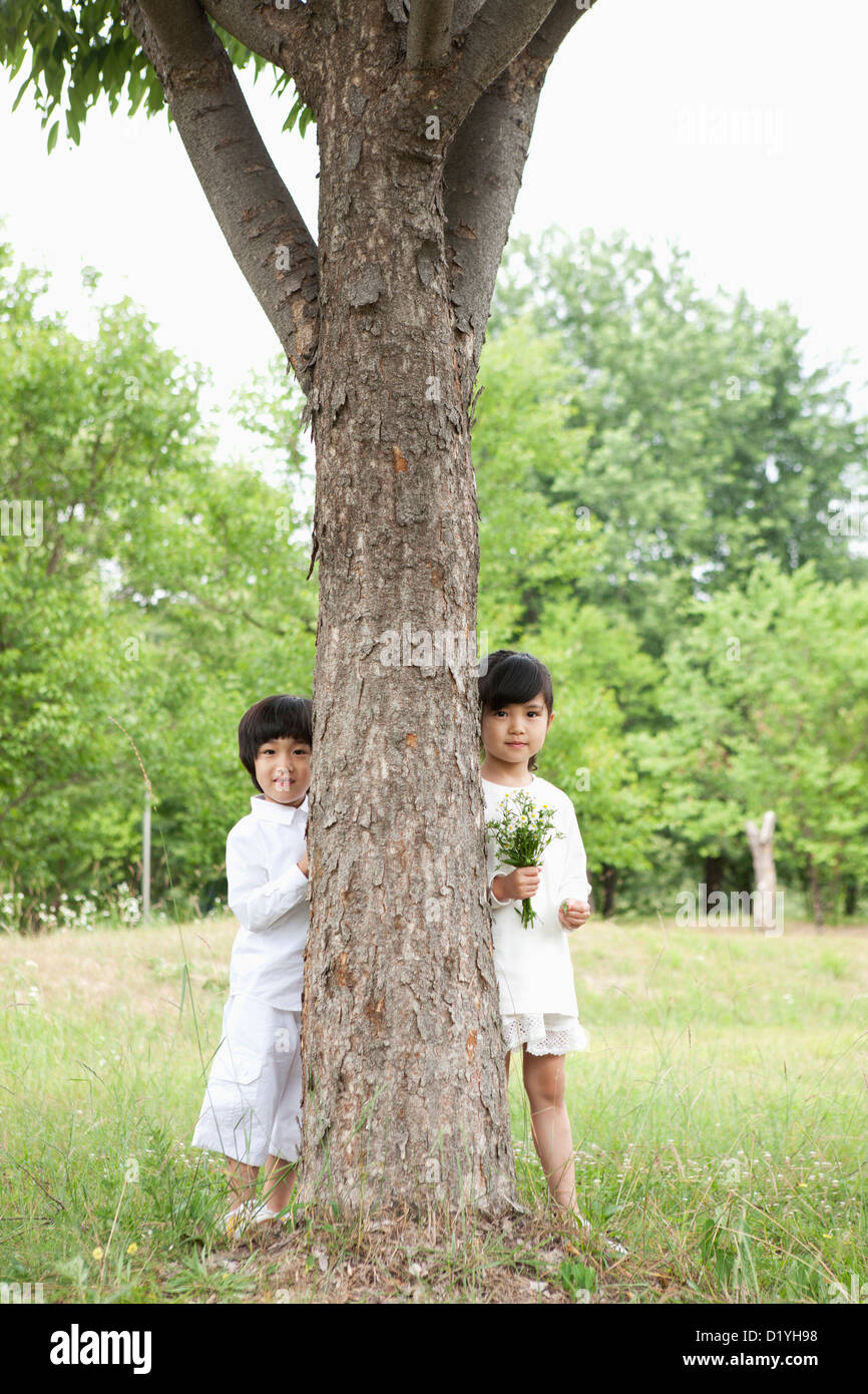 kids standing behind a tree Stock Photo - Alamy