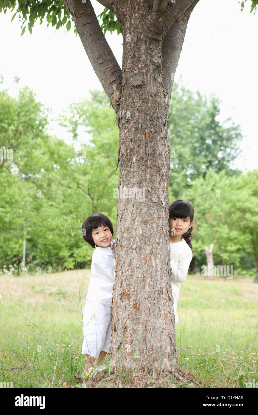 kids standing behind a tree Stock Photo - Alamy
