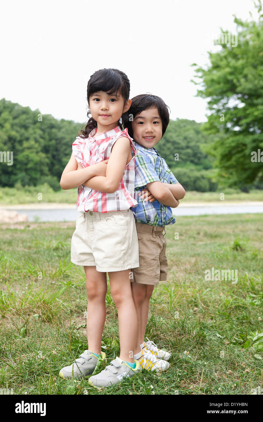 two kids posing with their back against each other Stock Photo - Alamy
