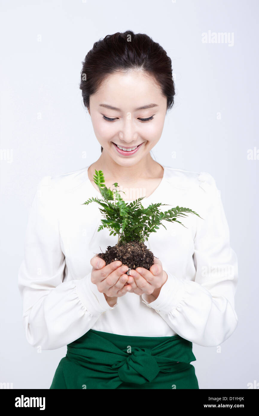 a woman in green skirt looking at a plant with roots in her hands Stock ...