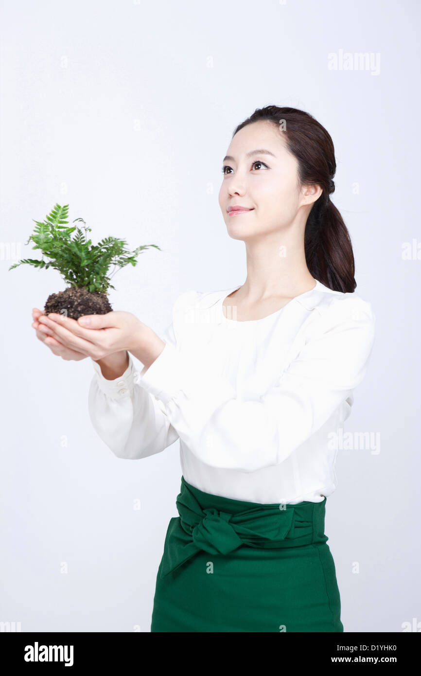 a woman in green skirt holding a plant with roots Stock Photo - Alamy