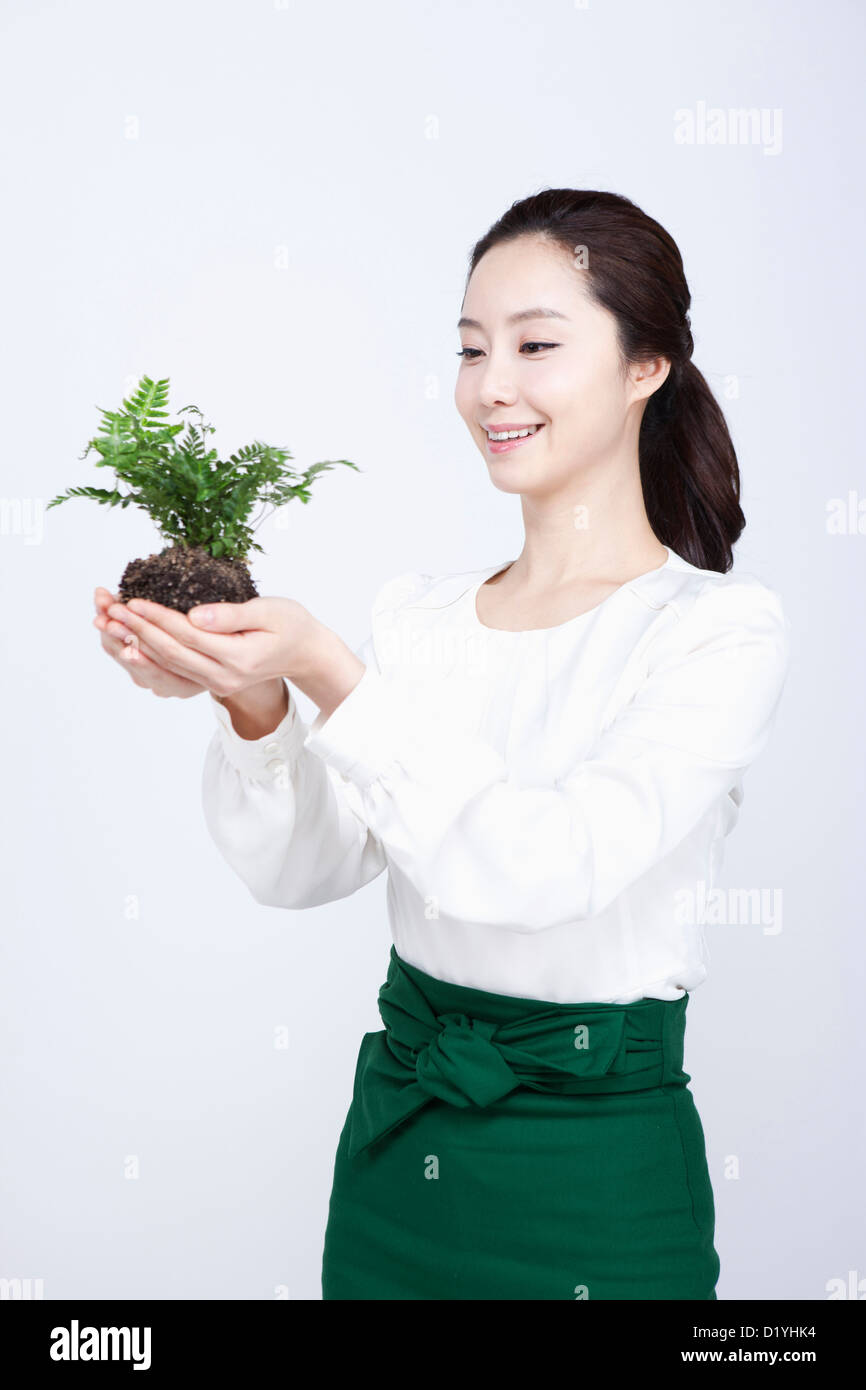 a woman in green skirt holding a plant with roots Stock Photo - Alamy