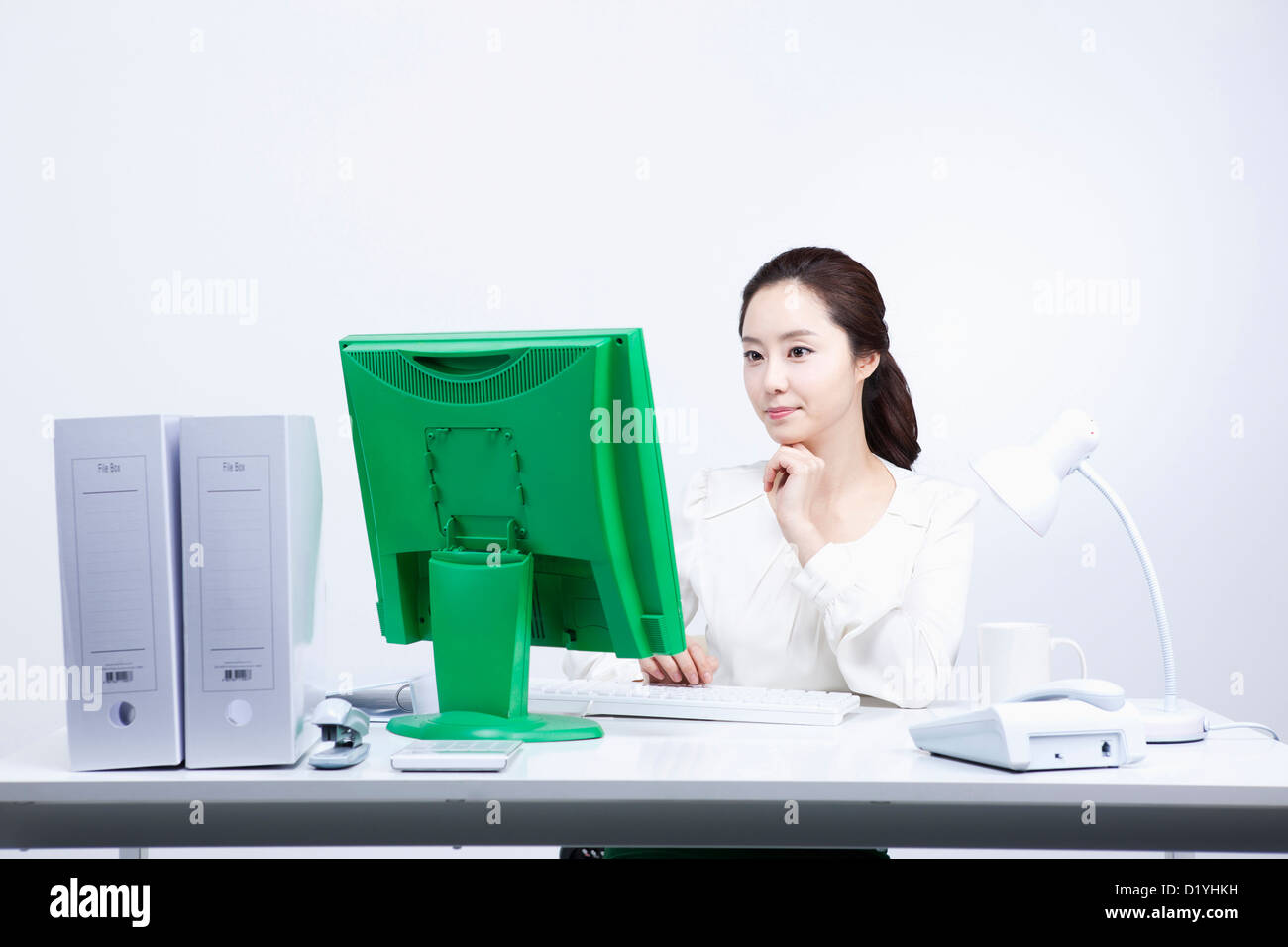 a woman sitting at office desk working with green computer Stock Photo ...