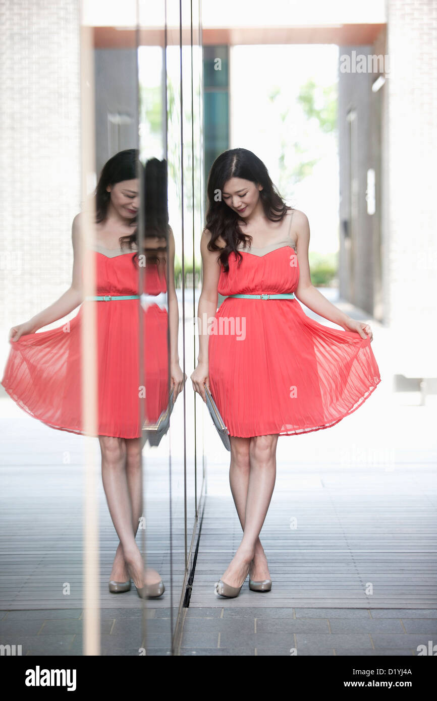 A woman in coral dress lifting up her dress Stock Photo - Alamy
