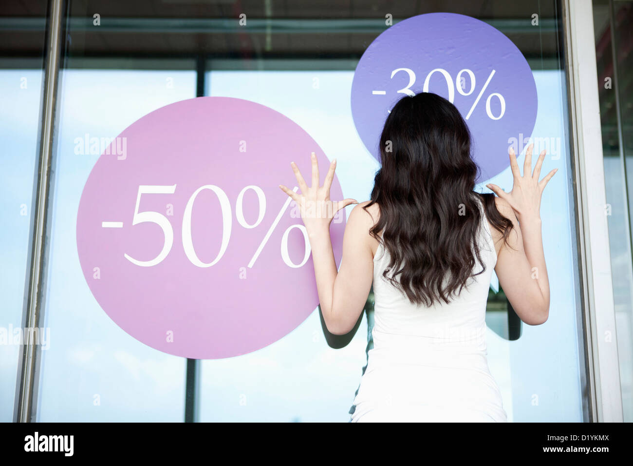 a lady touching a show window with sale signs Stock Photo - Alamy
