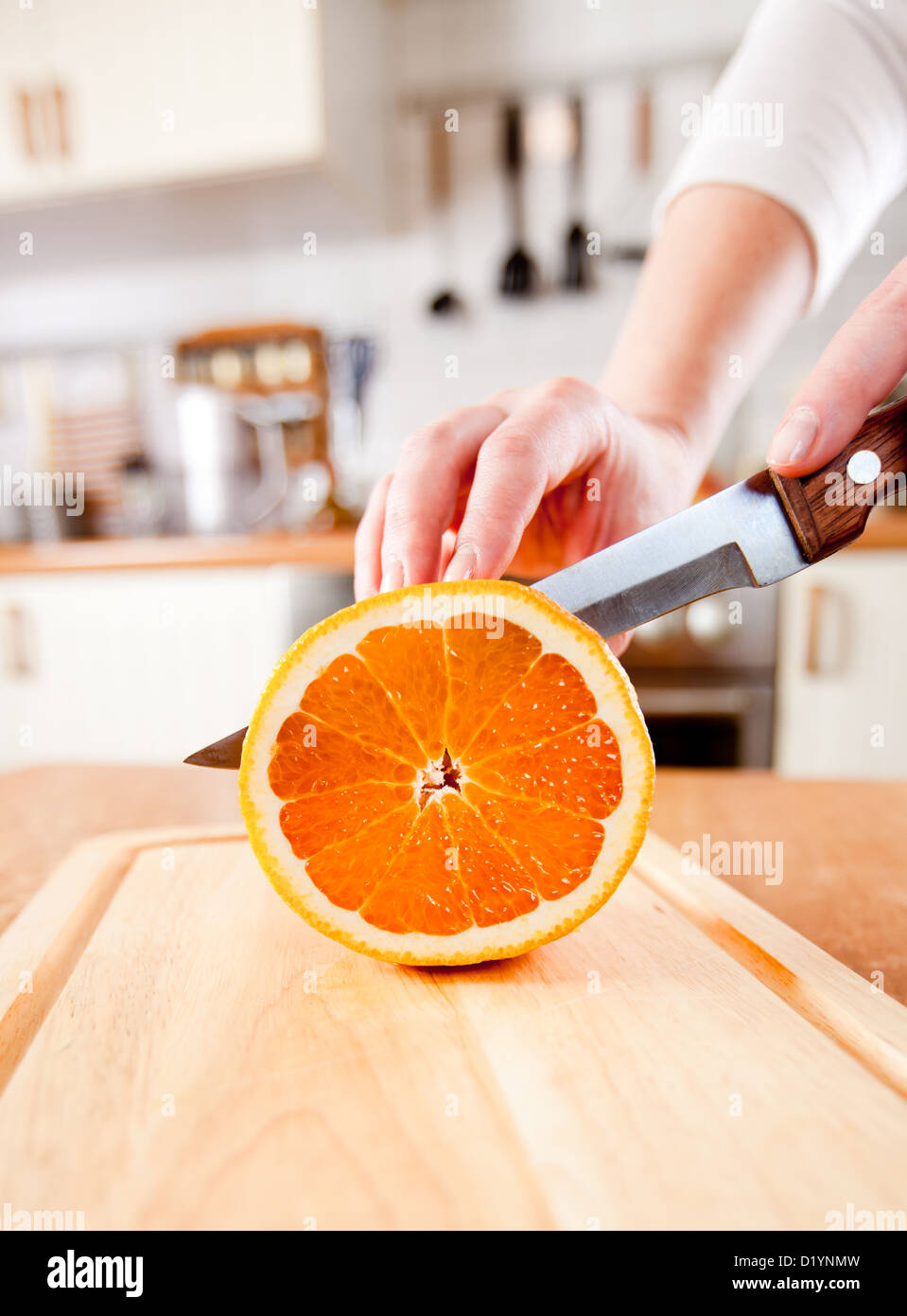 Woman's hands cutting fresh orange on kitchen Stock Photo - Alamy
