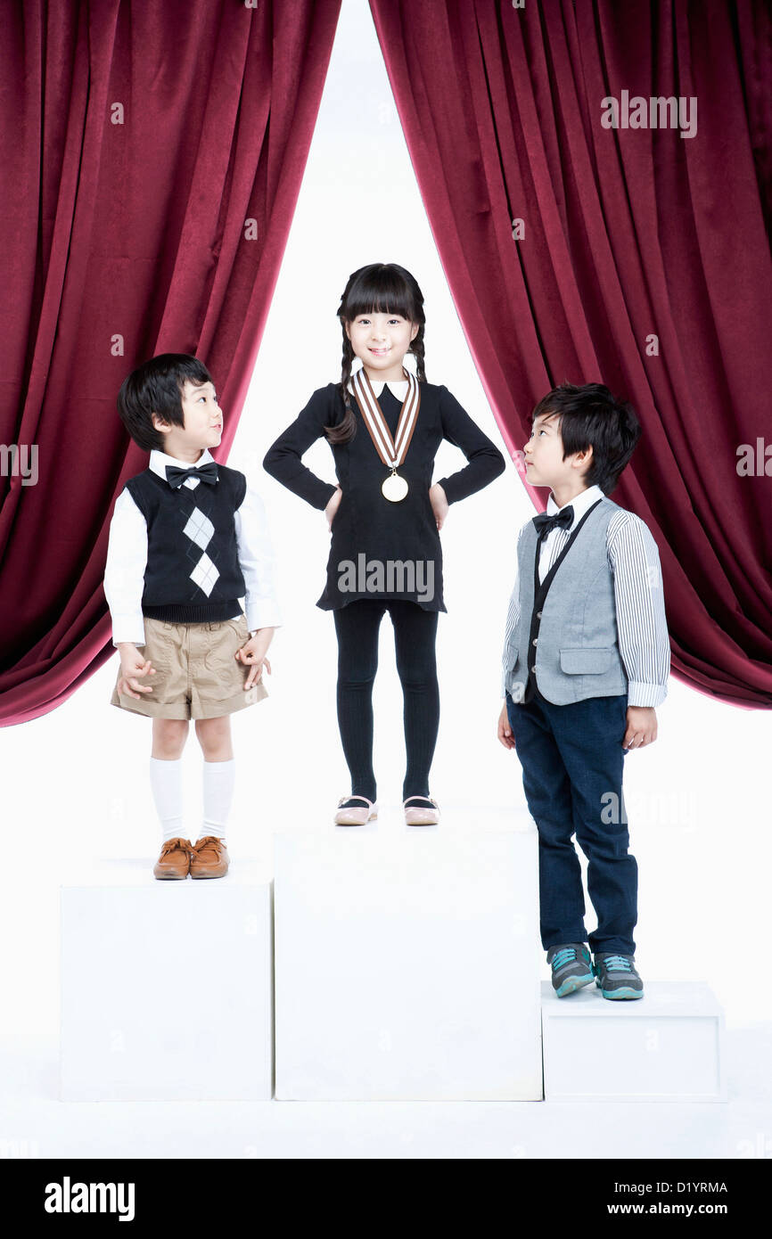 kids standing on podium with medals in front of red curtains Stock ...