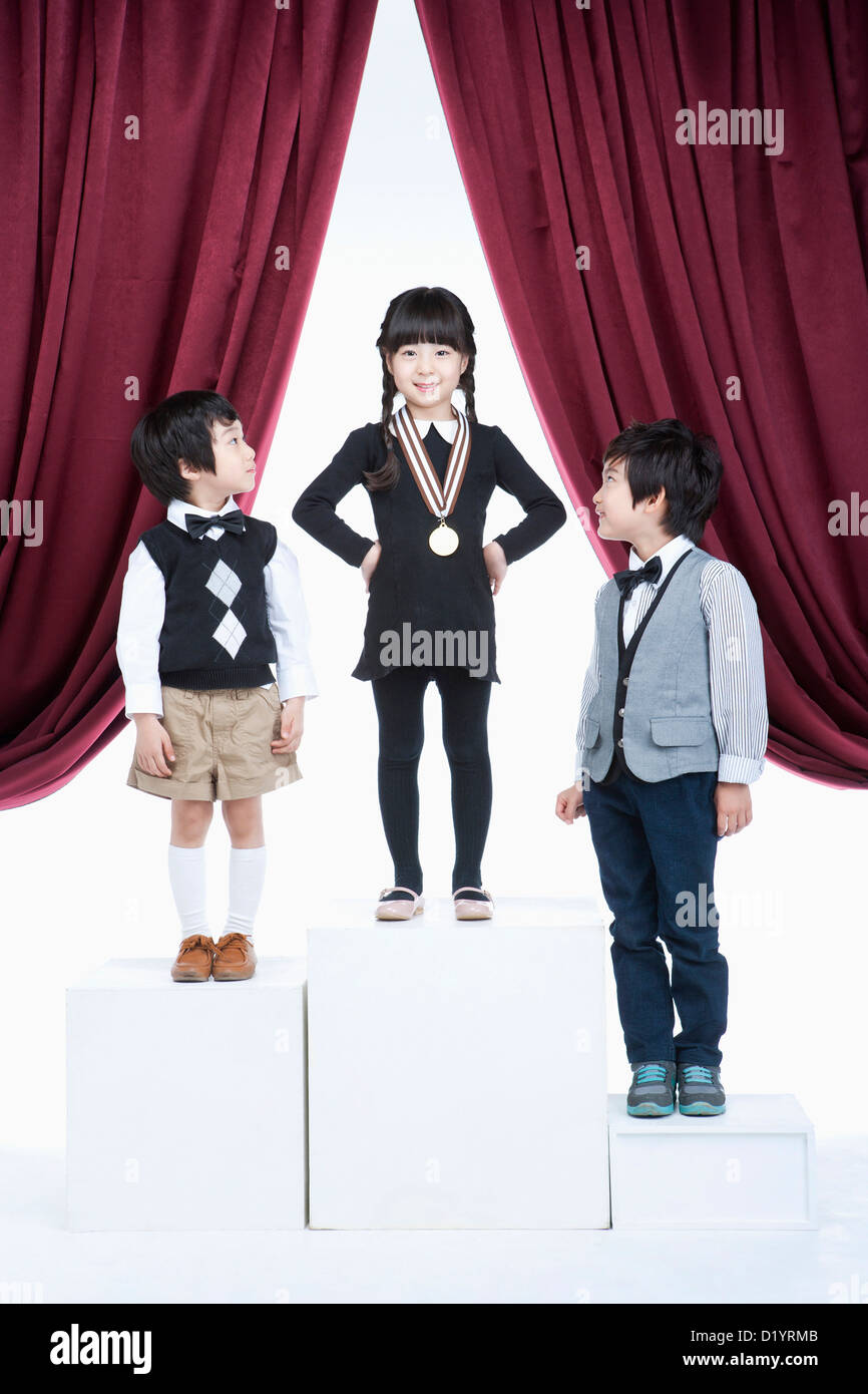 kids standing on podium with medals in front of red curtains Stock ...