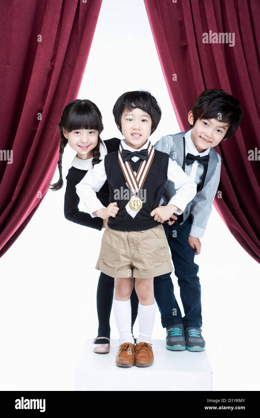 two kids posing behind a boy with a medal Stock Photo - Alamy