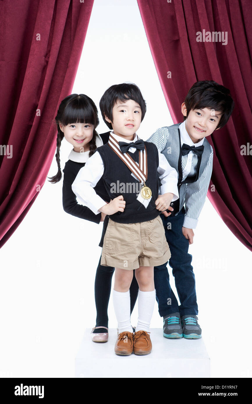 two kids posing behind a boy with a medal Stock Photo - Alamy