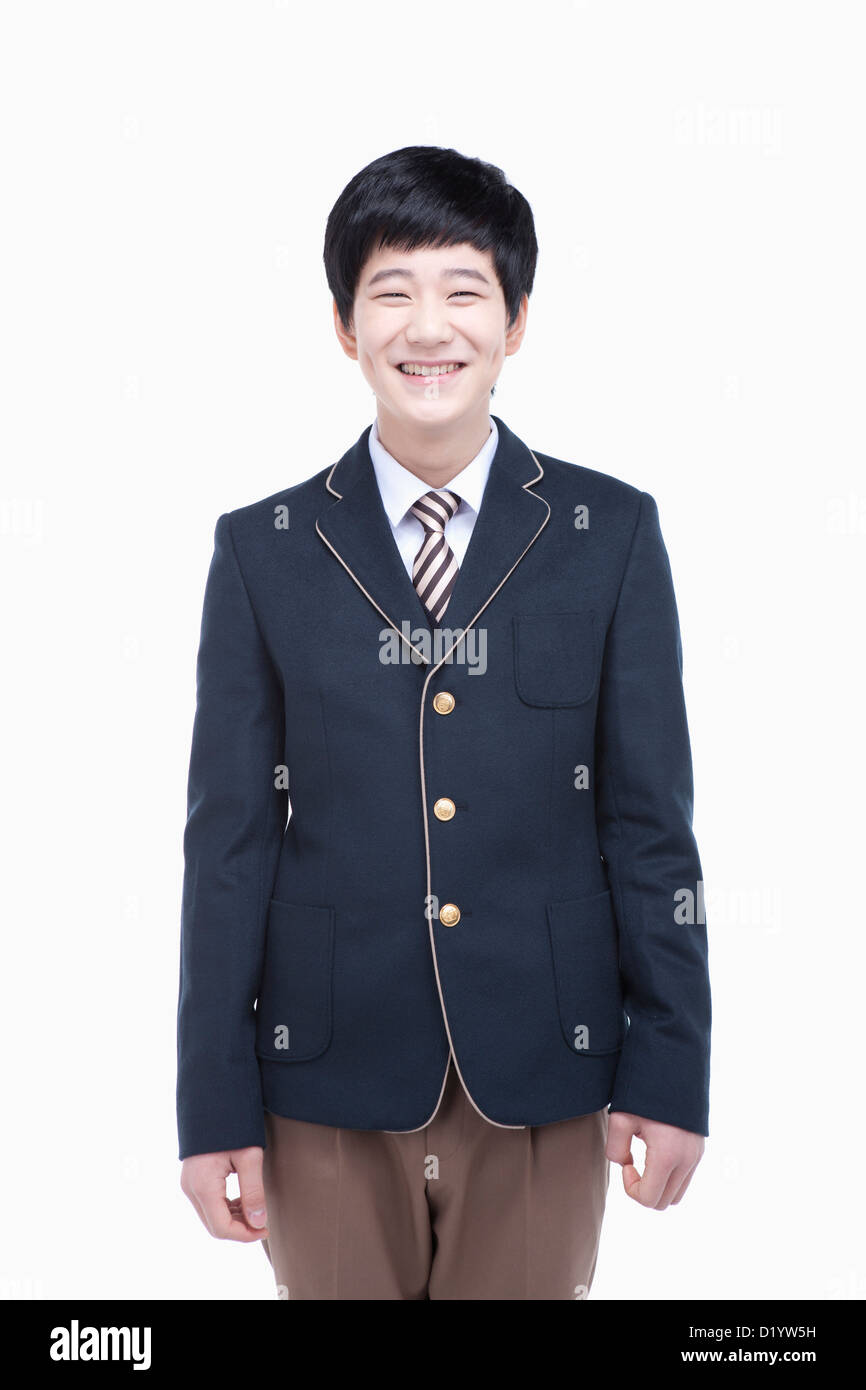 a male student with school uniform smiling while standing up straight ...