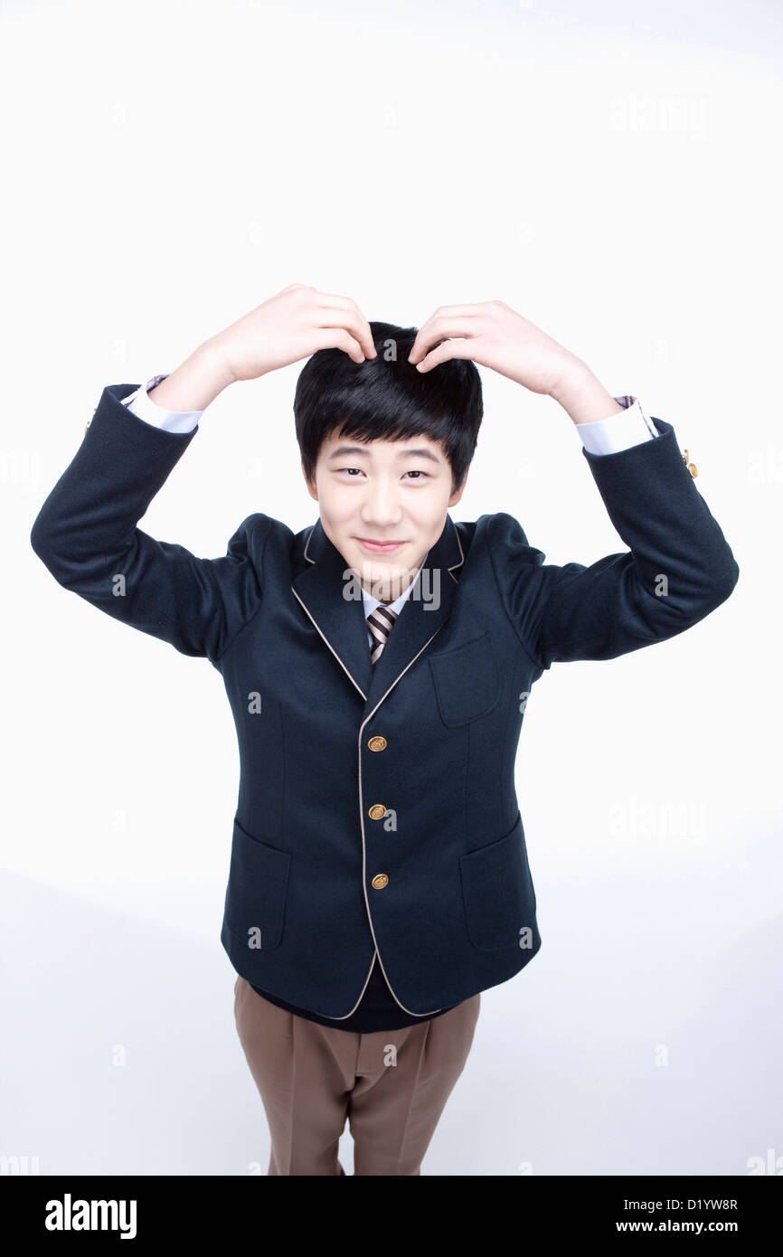 a male student wearing school uniform making heart symbol with arms ...