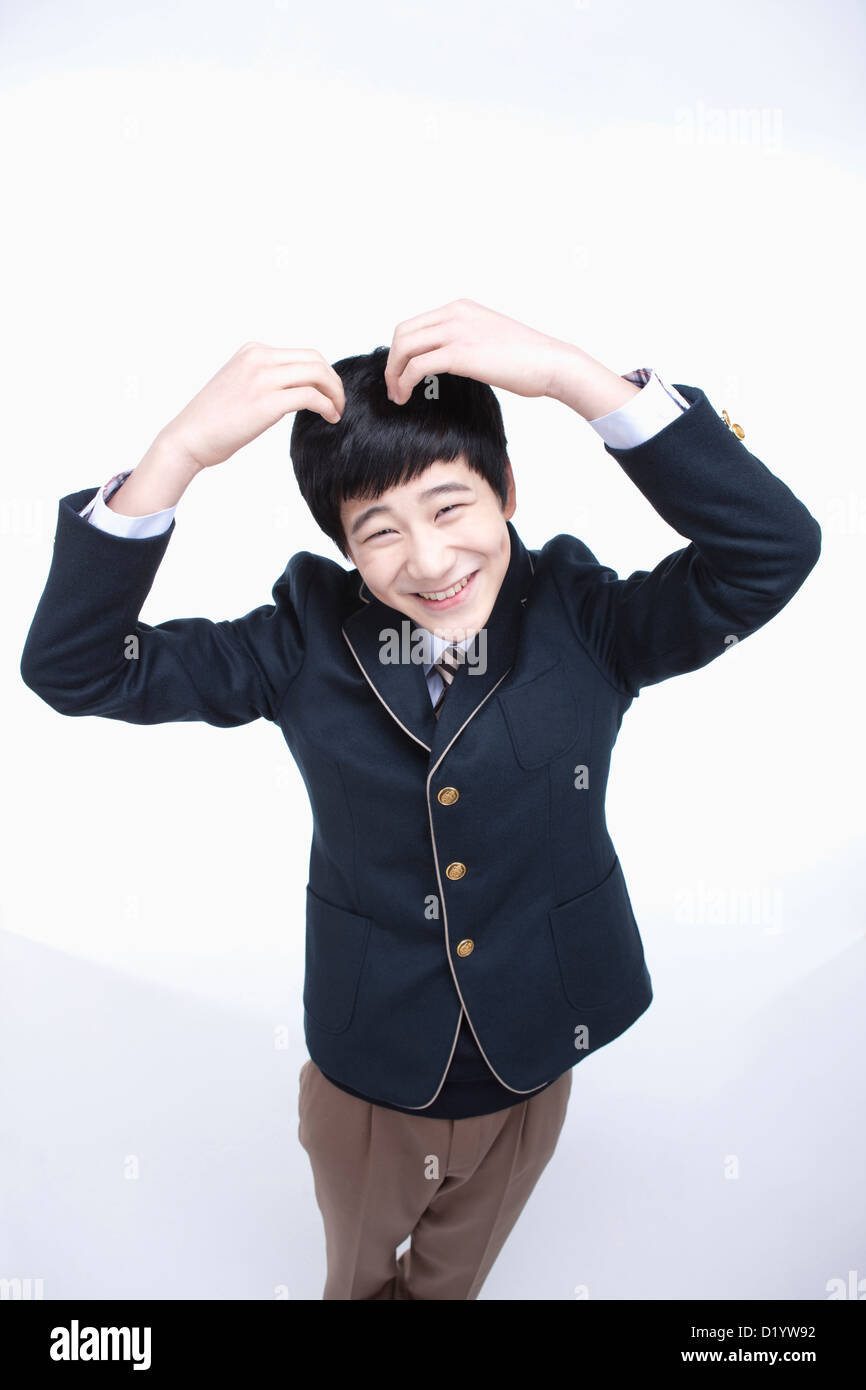 a male student wearing school uniform making heart symbol with arms ...