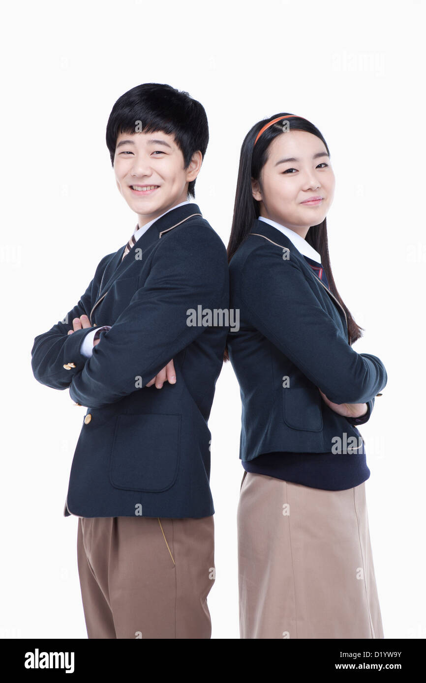 a female and a male student in school uniform posing with their backs ...