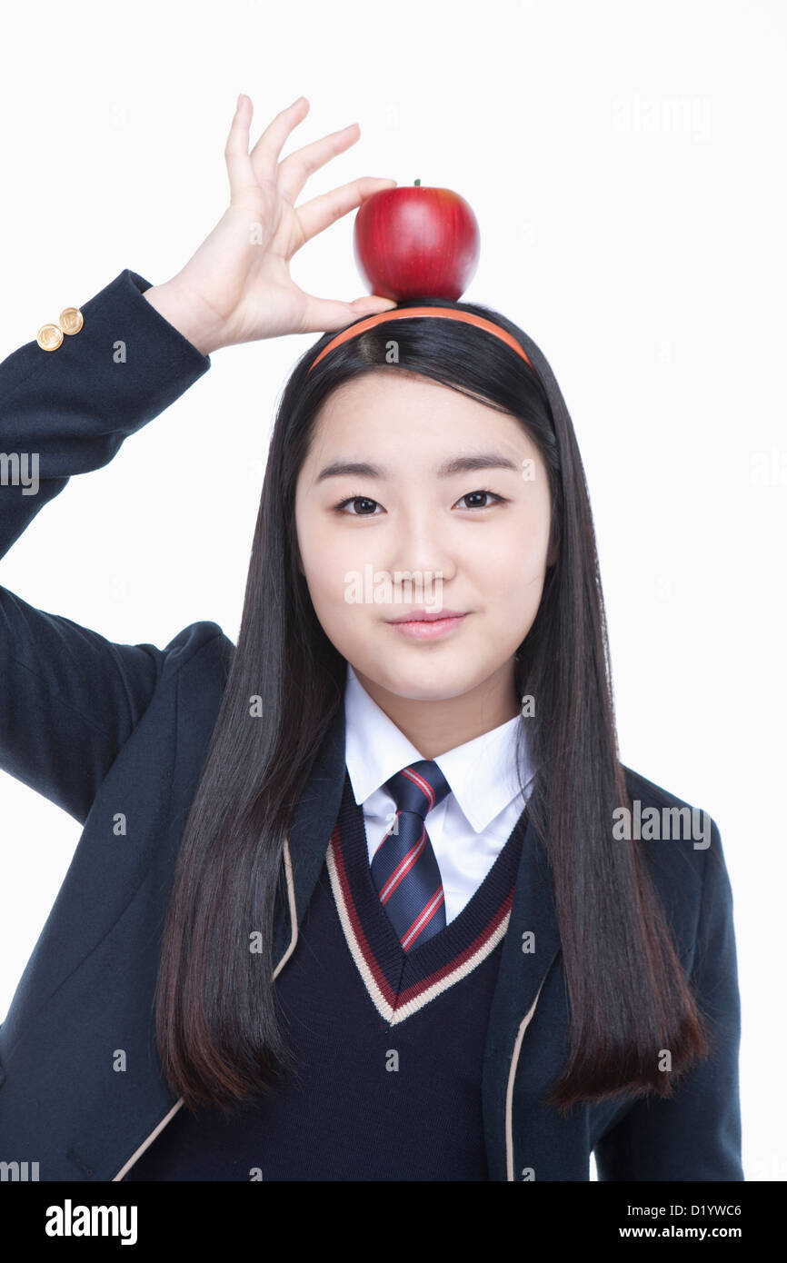 a female student wearing school uniform with an apple on her head Stock ...