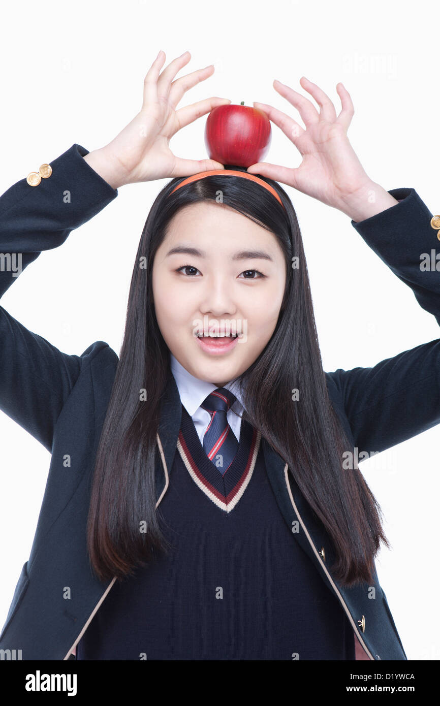 a female student wearing school uniform balancing an apple on her head ...