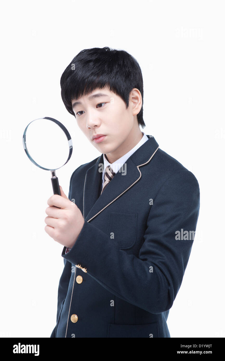 a male student with school uniform looking through a magnifying glass ...