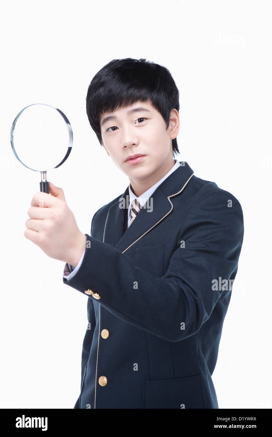 a male student with school uniform holding a magnifying glass Stock ...