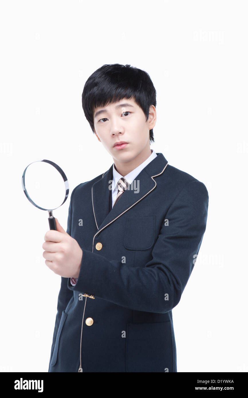 a male student with school uniform holding a magnifying glass Stock ...