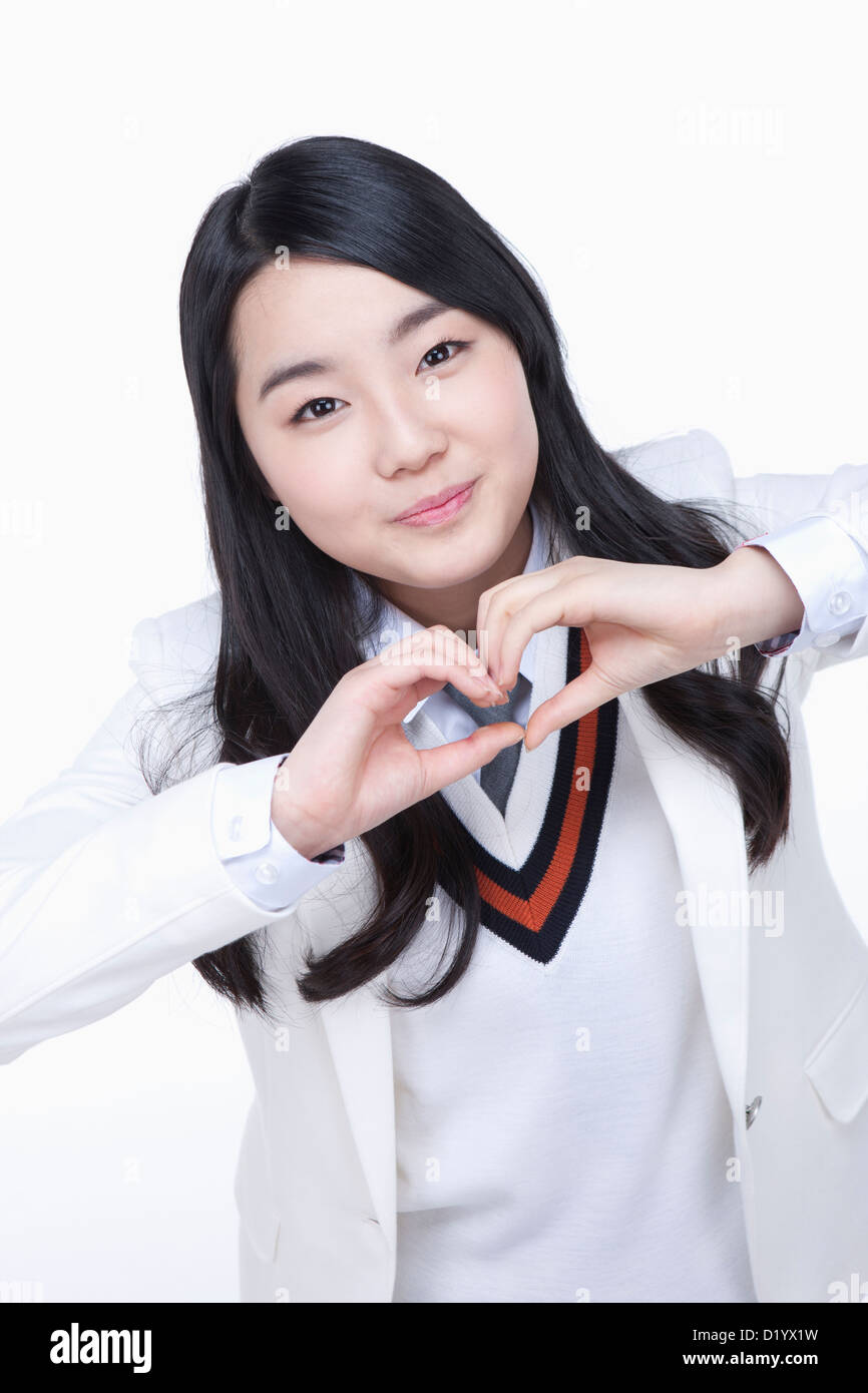 a female student in school uniform making heart symbol with her hands ...