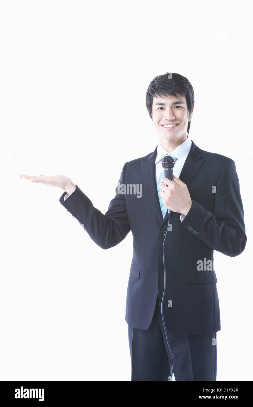 a businessman in a black suit explaining something using microphone ...