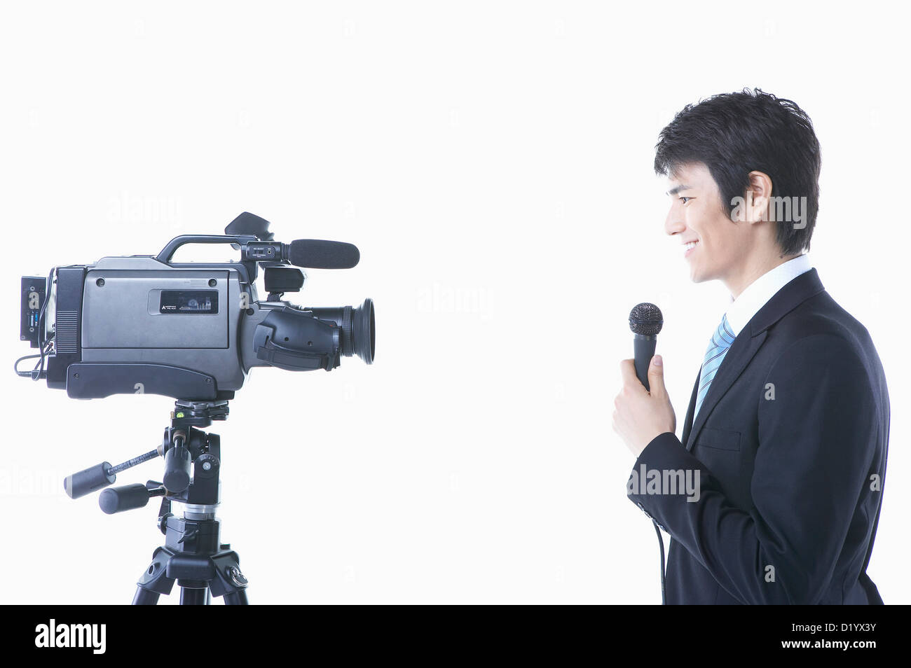 a man in a black suit speaking with a microphone in front of a studio ...