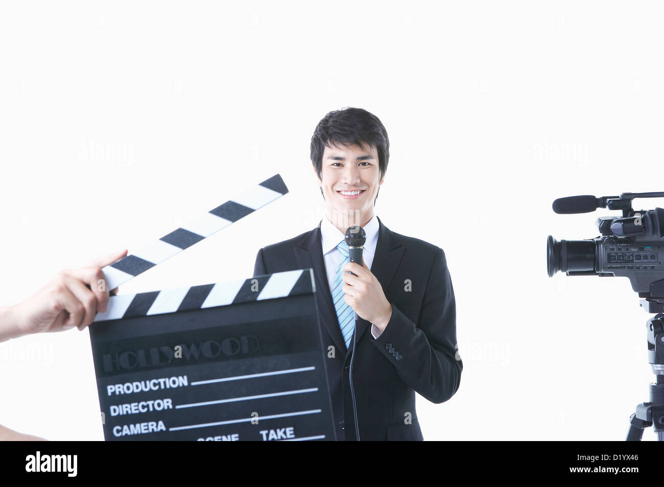 a studio camera and action board in front of man in a black suit with a ...