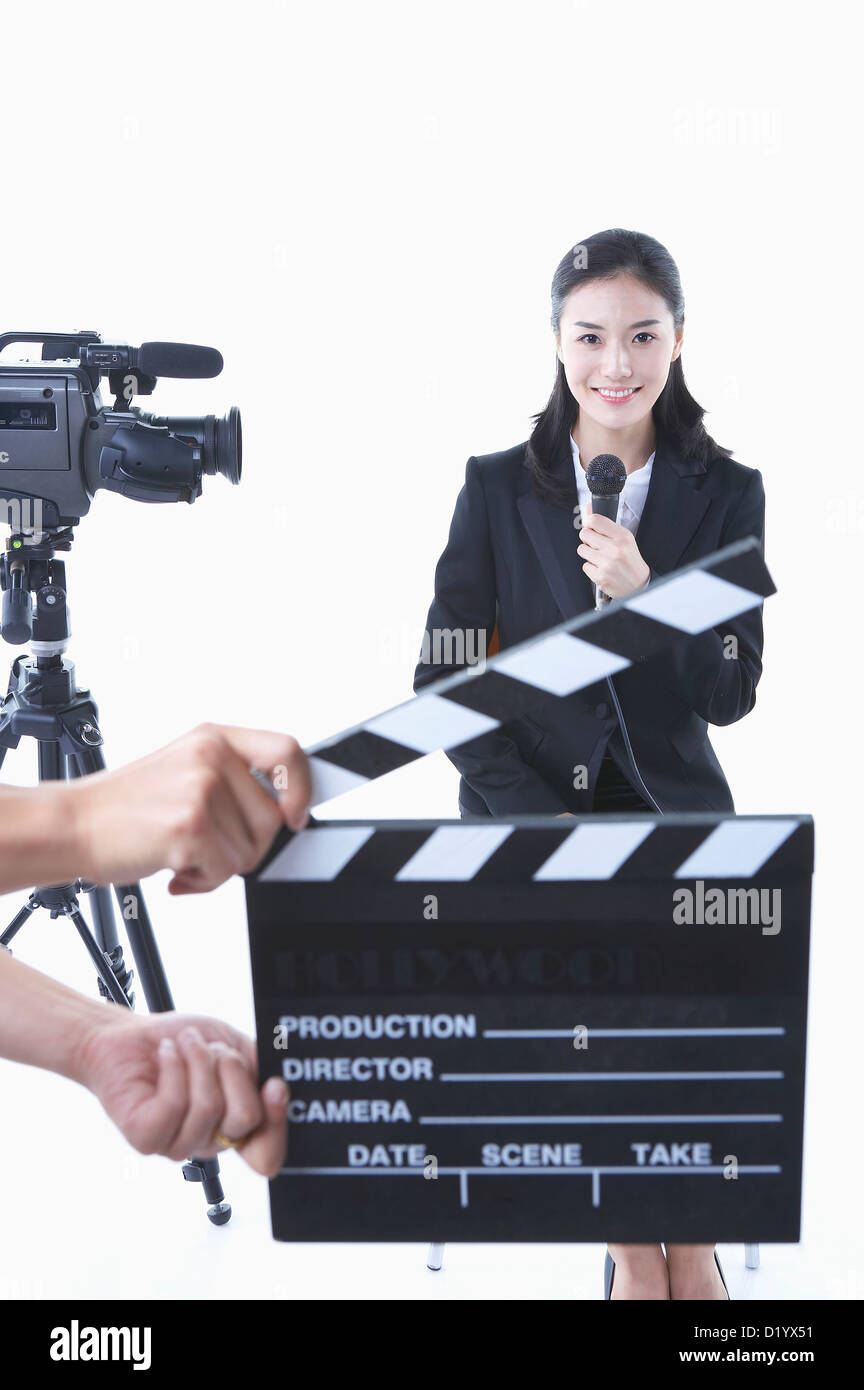 a studio camera and action board in front of woman in a black suit with ...