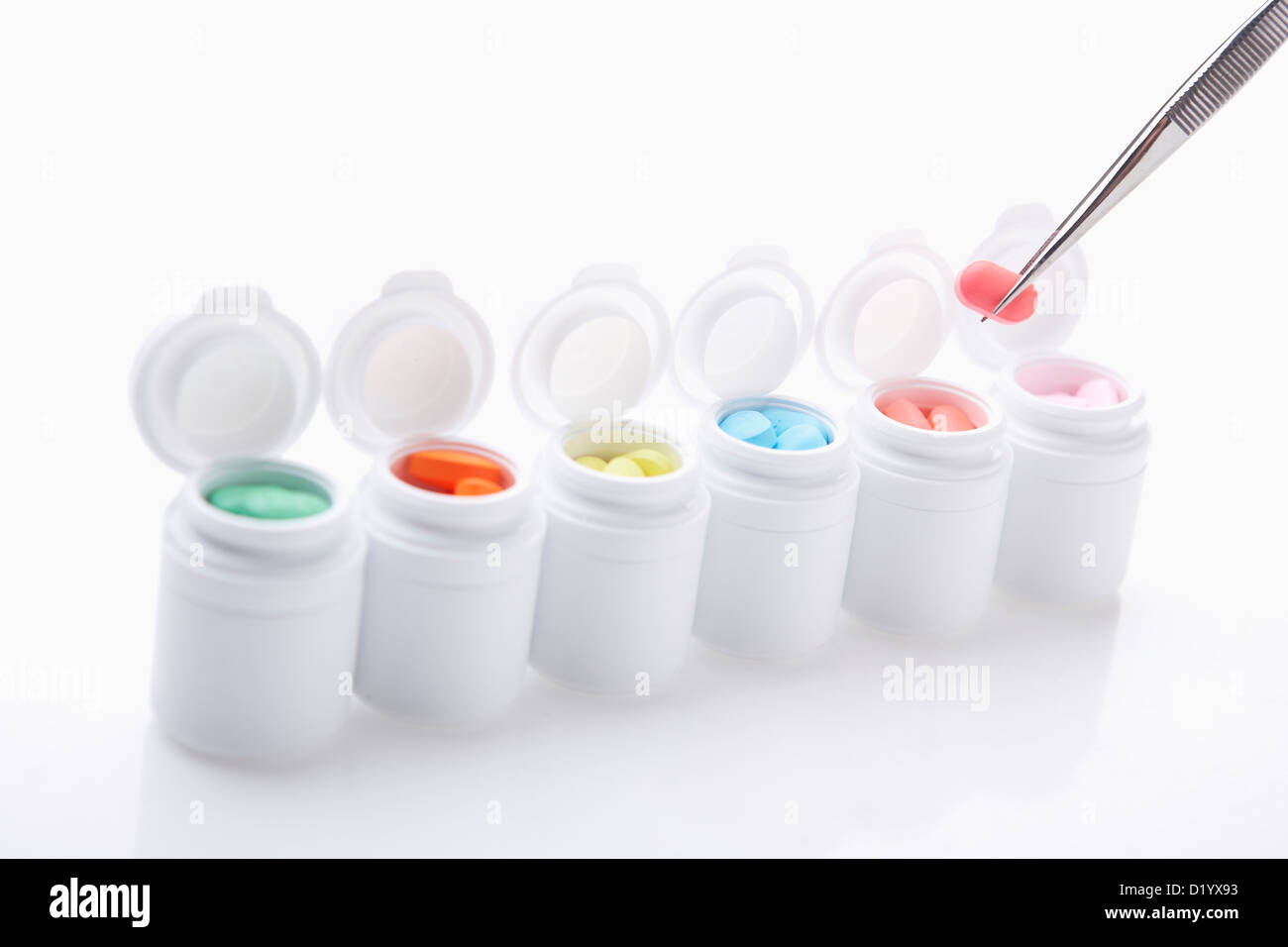 white drug bottles filled up with different colours of medicine tablets ...