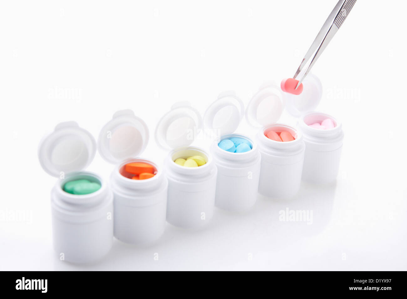 white drug bottles filled up with different colours of medicine tablets ...