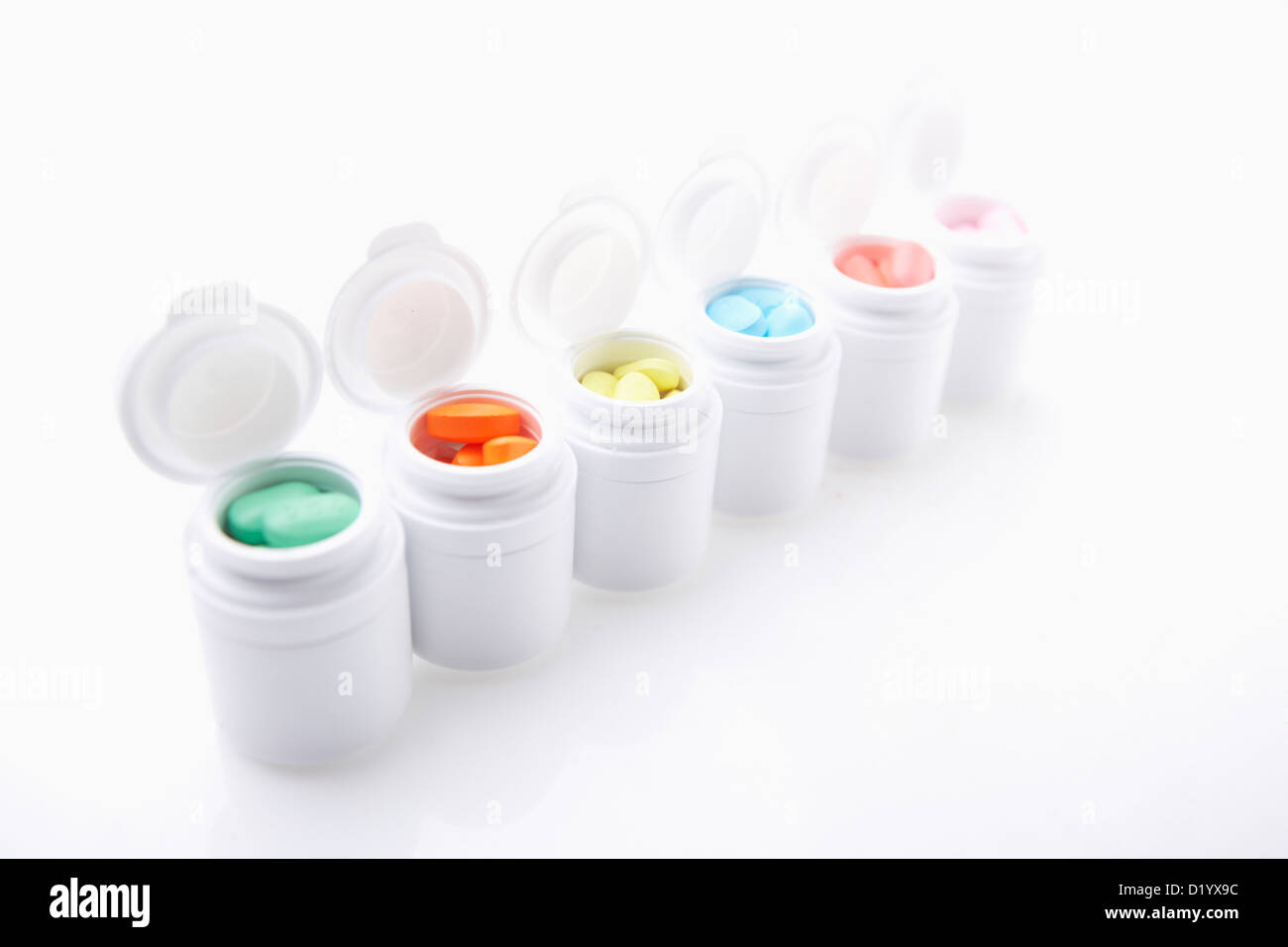 white drug bottles filled up with different colours of medicine tablets ...
