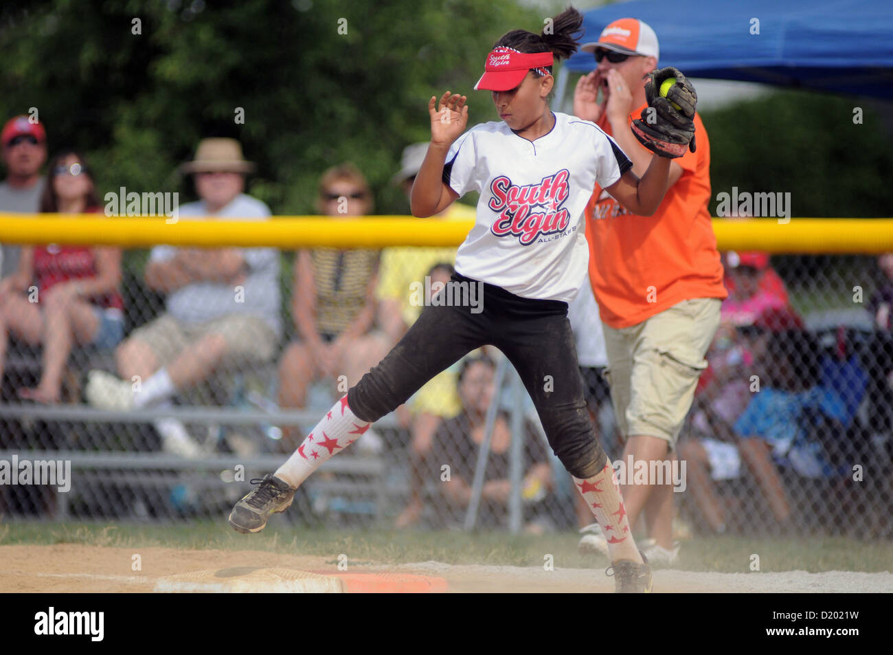 Softball First baseman extends to tag the bag after leaping to capture ...