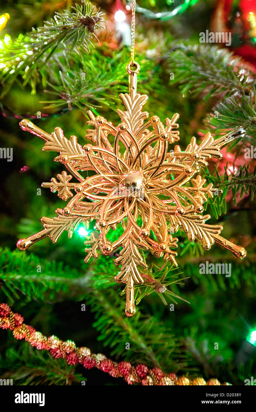 Shiny golden filigree snowflake ornament hanging in the Christmas tree ...