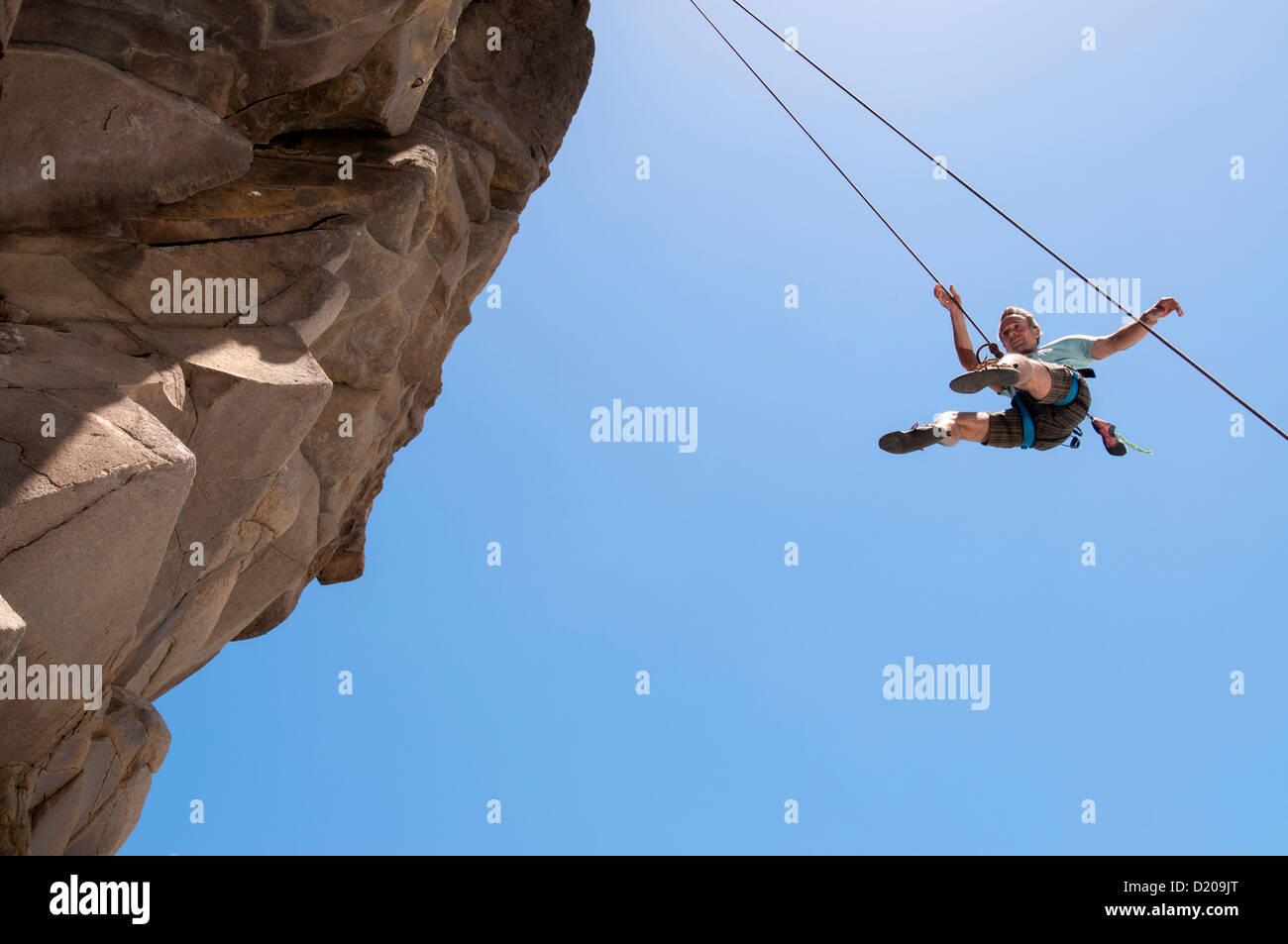 Mature Man Abseiling down and swining on rope Stock Photo - Alamy