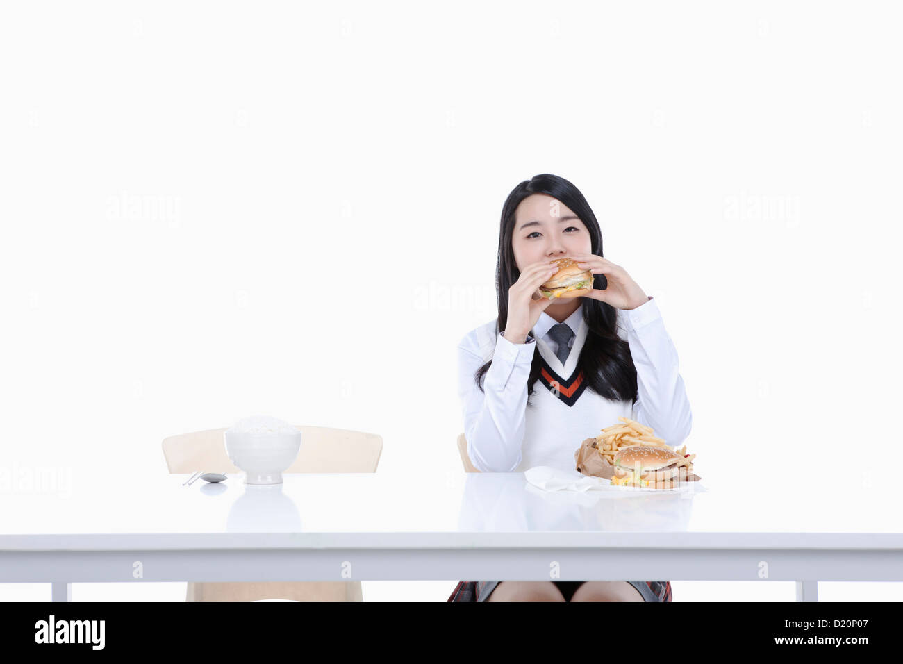 a female student with school uniform biting a burger Stock Photo - Alamy