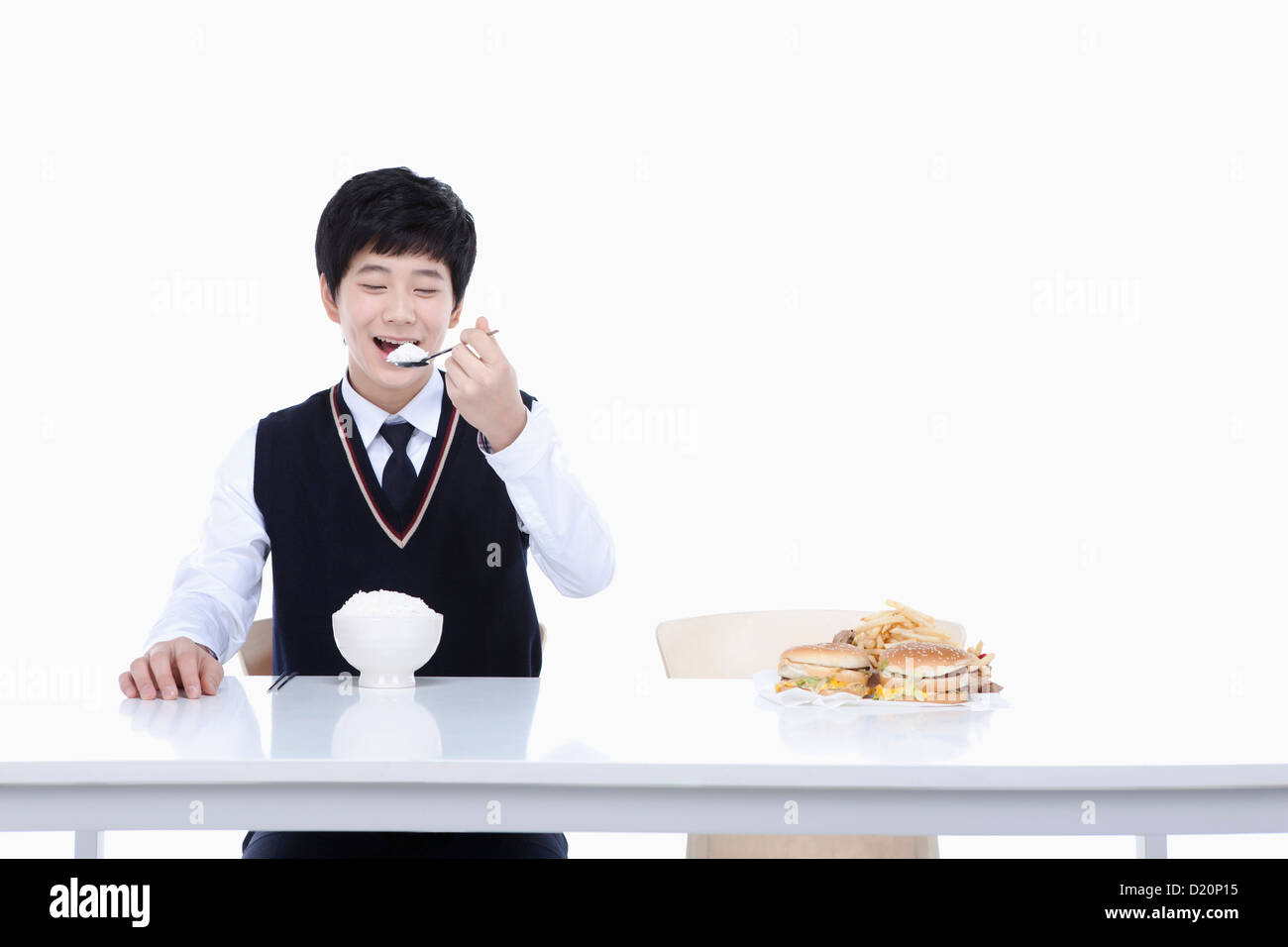 a male student with school uniform eating rice Stock Photo - Alamy