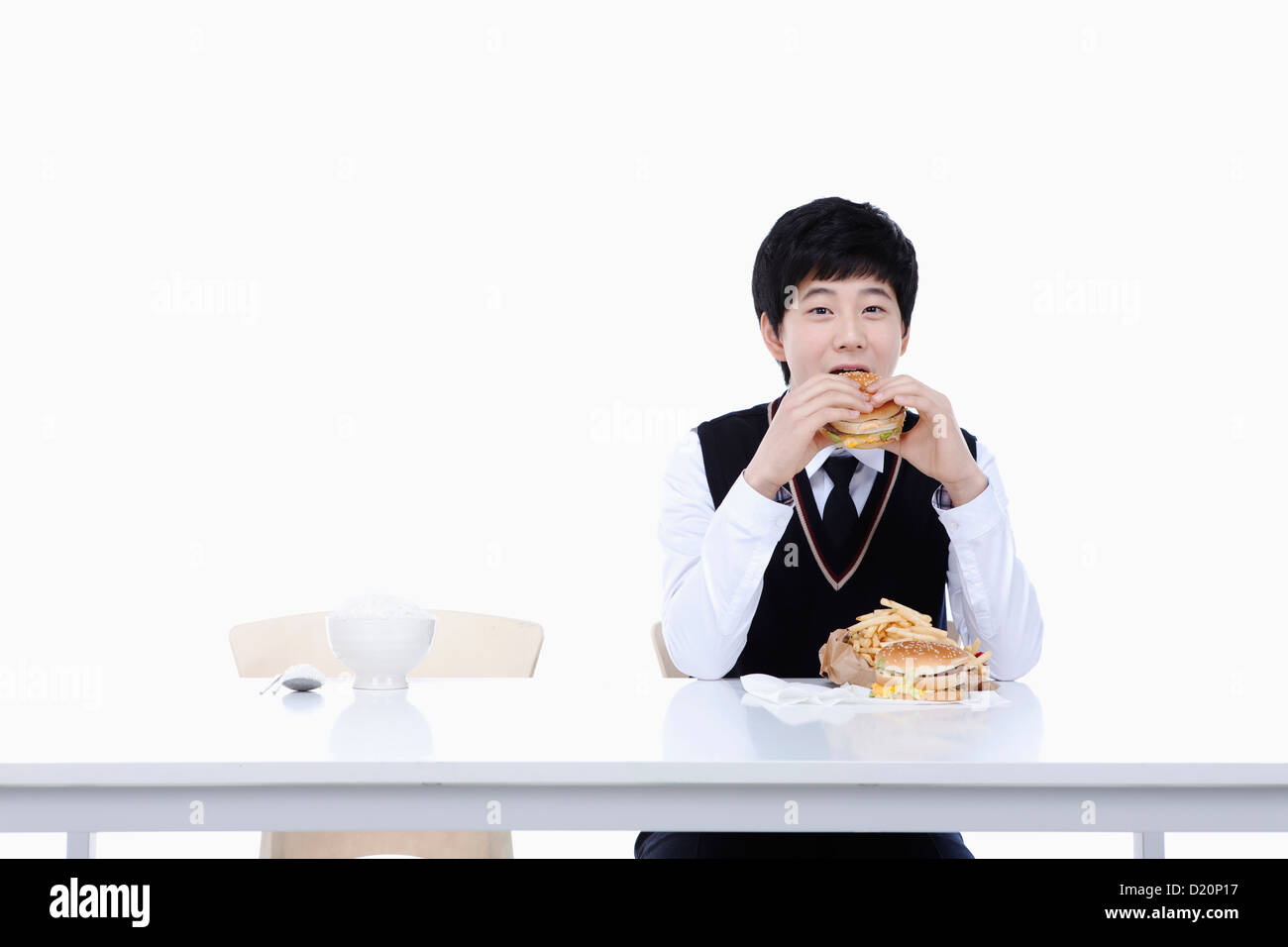 a male student with school uniform eating burgers Stock Photo - Alamy