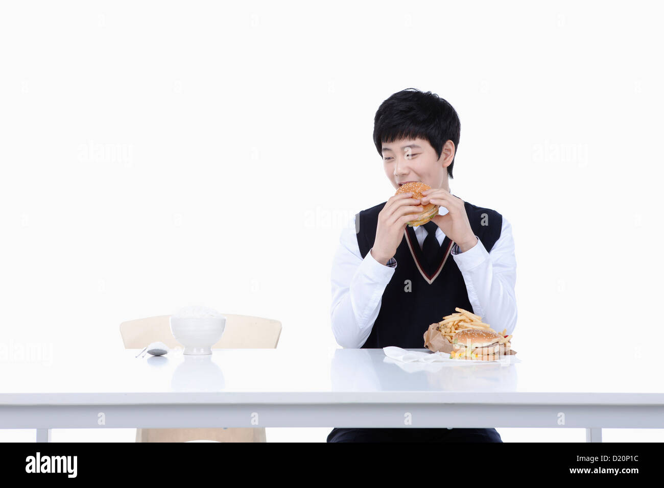 a male student with school uniform eating burgers while staring at rice ...