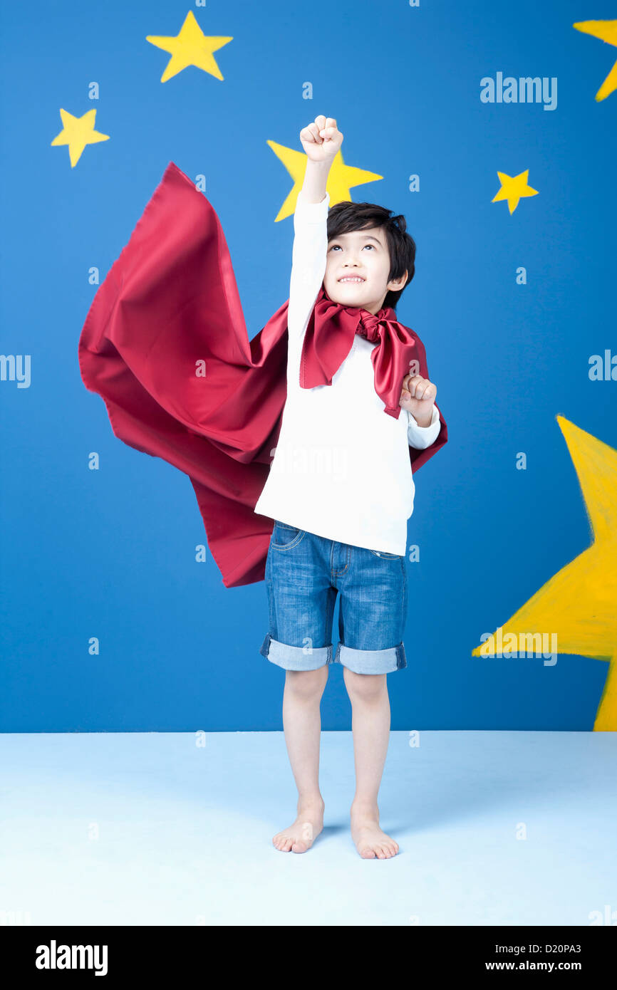 a boy posing like a superman with fluttering red cape Stock Photo - Alamy
