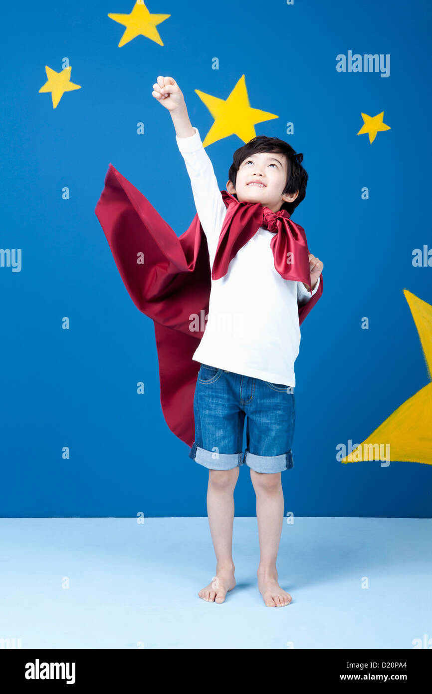 a boy posing like a superman with fluttering red cape Stock Photo - Alamy